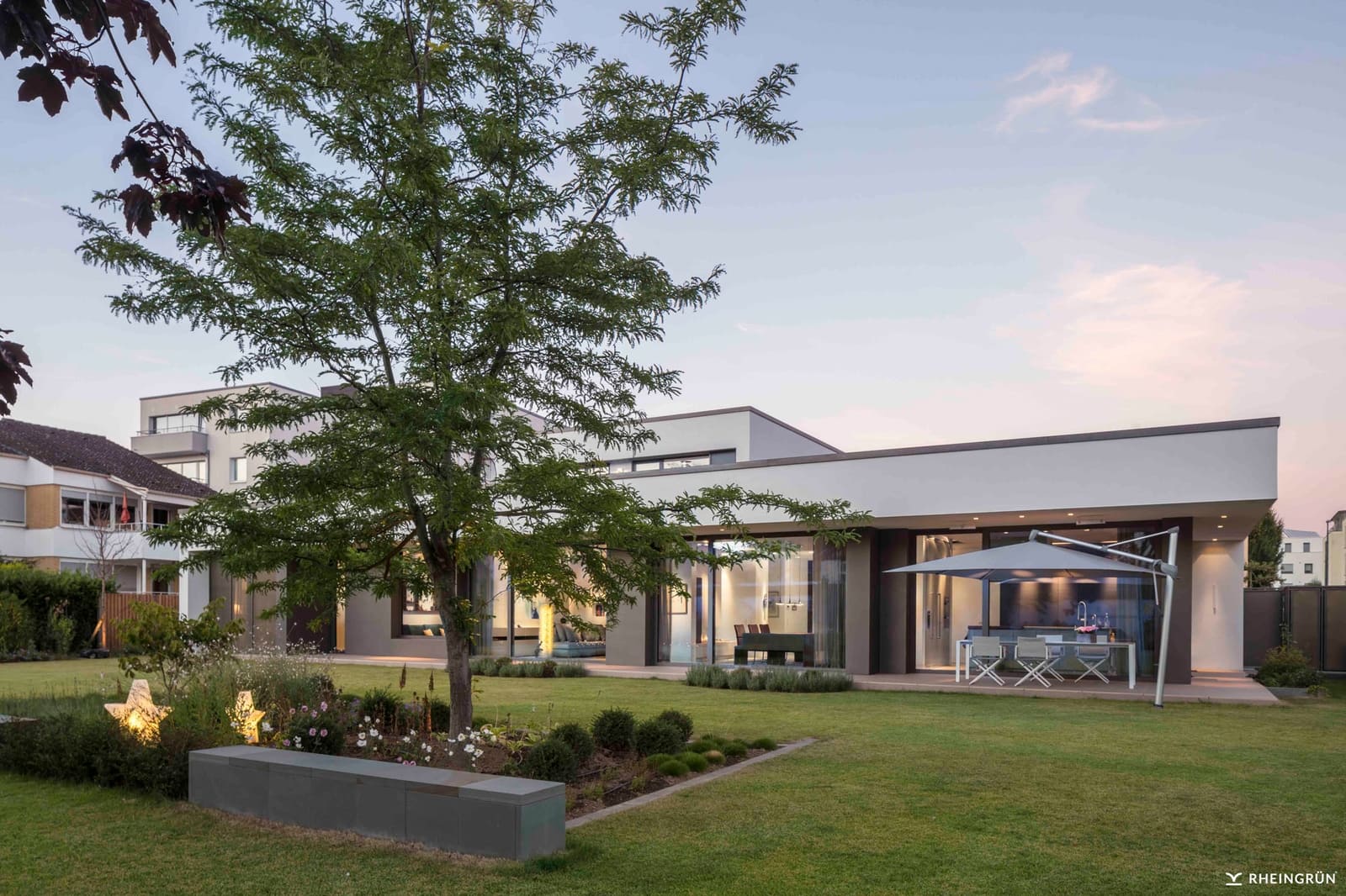 Villa mit Flachdach, großer Rasenfläche und akzentuierter Bepflanzung ...